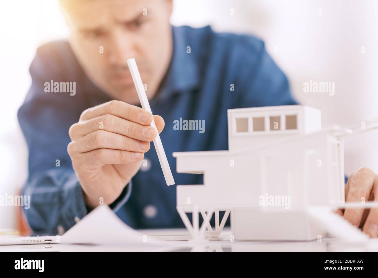 Professional architect working at office desk, he is assembling an ...