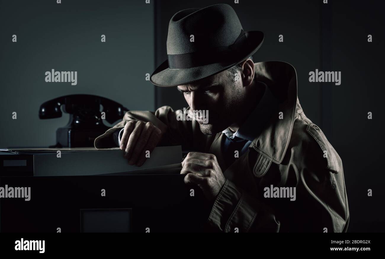 Vintage undercover criminal spy stealing files in a filing cabinet late ...