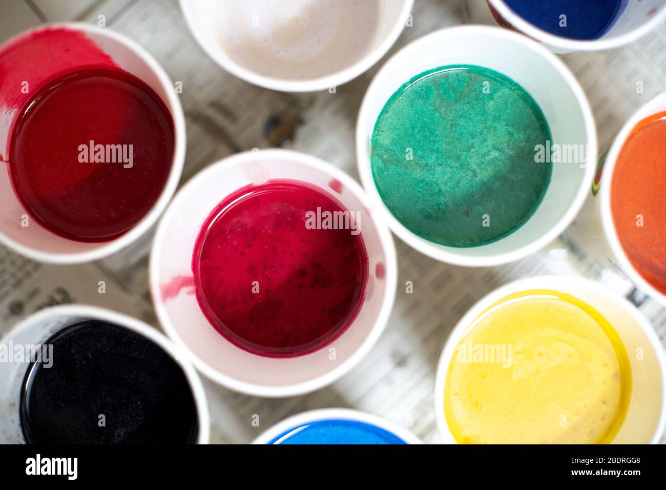 Overhead shot of colorful liquid in paper cups showing soap, food color ...