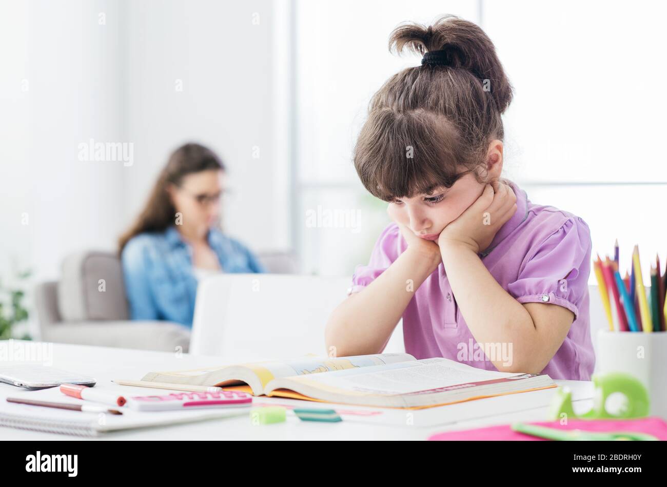 Lazy bored young girl studying and doing her homework at home, she is ...
