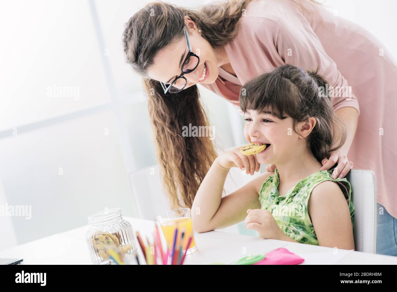 Cute preschool girl having a snack with her mother, she is eating some ...