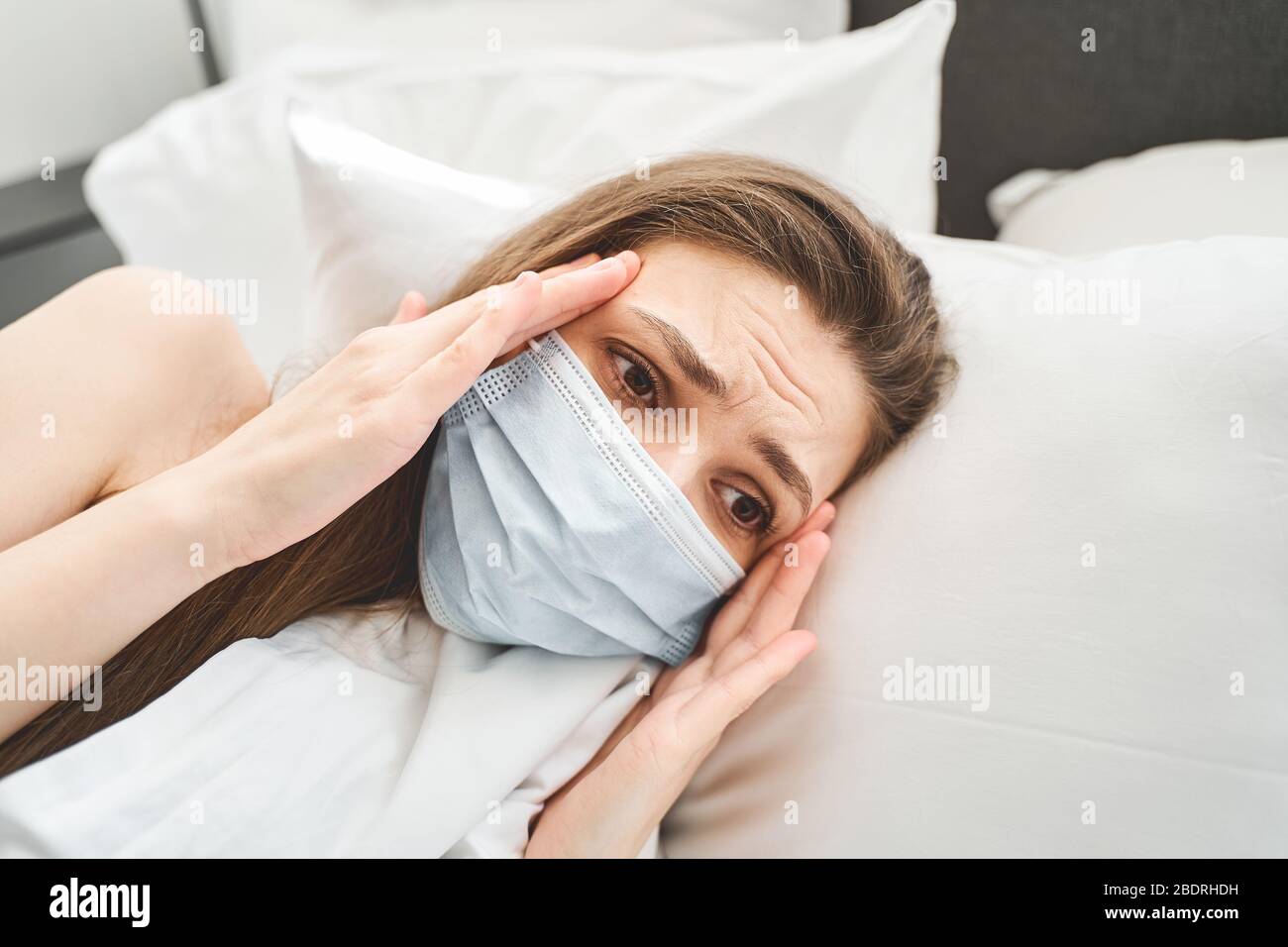 Girl with a splitting headache lying in bed Stock Photo - Alamy
