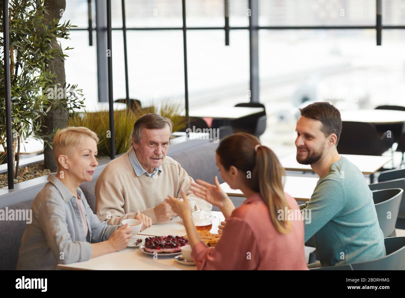 Family of four sitting at the table having breakfast together and ...