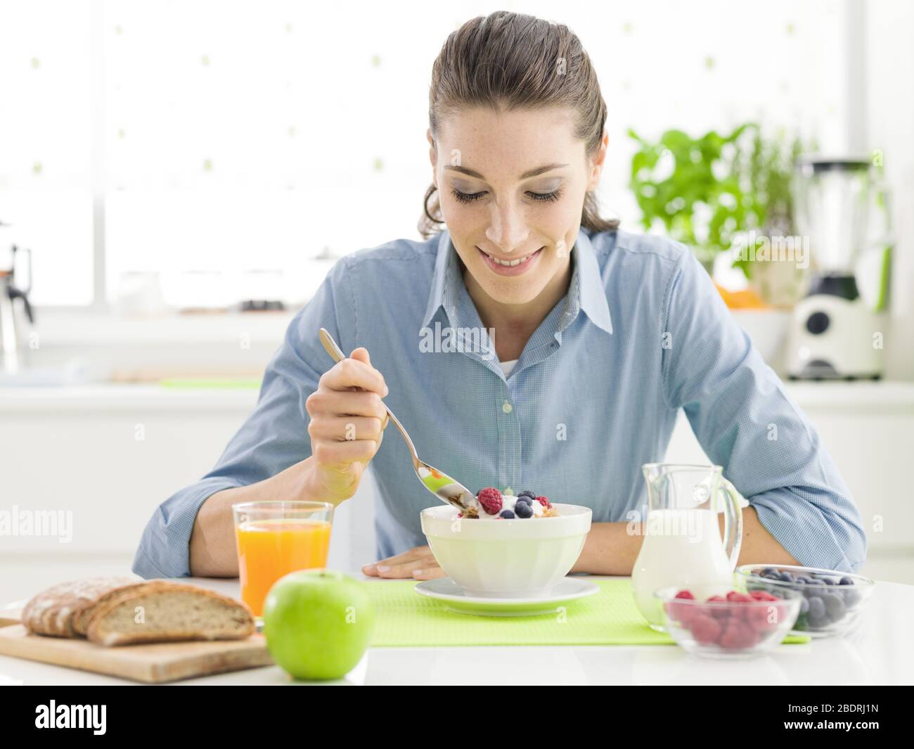 Smiling happy woman having a delicious healthy breakfast at home, she ...