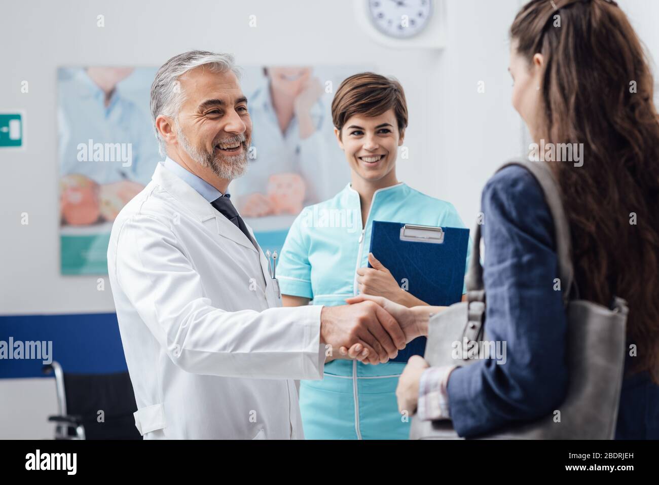 Medical staff welcoming a patient at the clinic: the doctor is giving ...