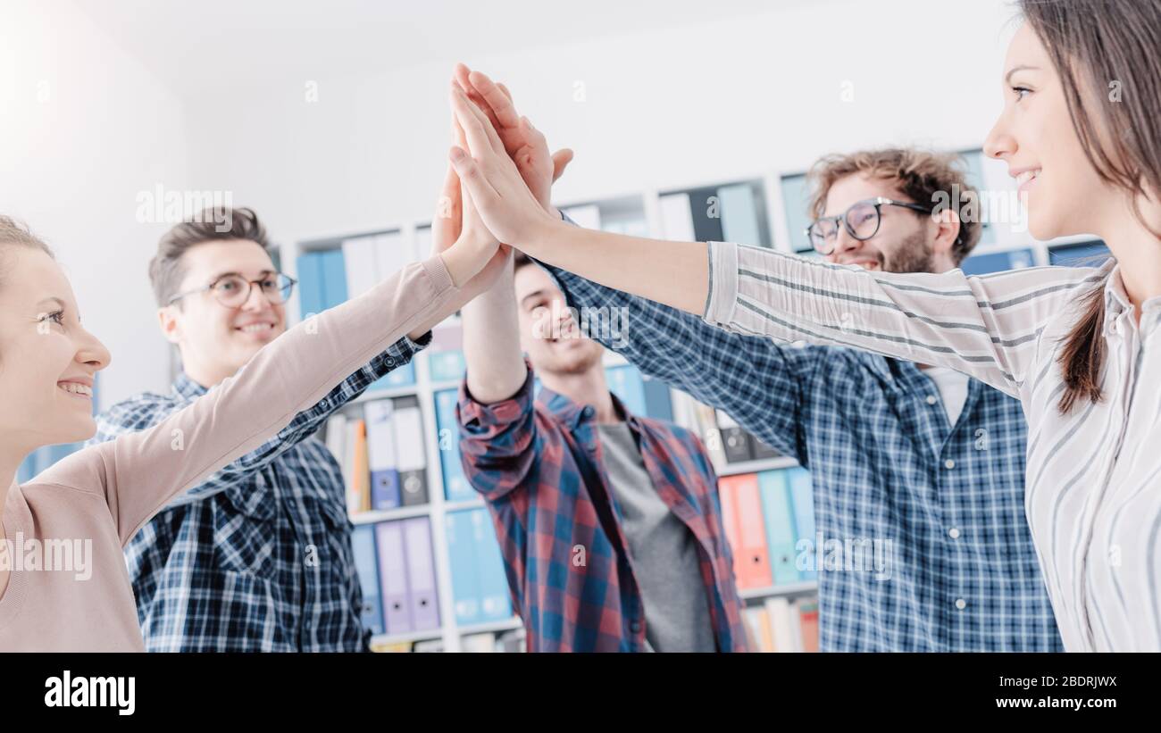 Young business people meeting in the office and joining hands together ...