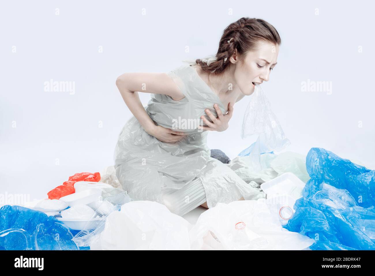 The world is choking on plastic. The girl is sitting on the floor in ...