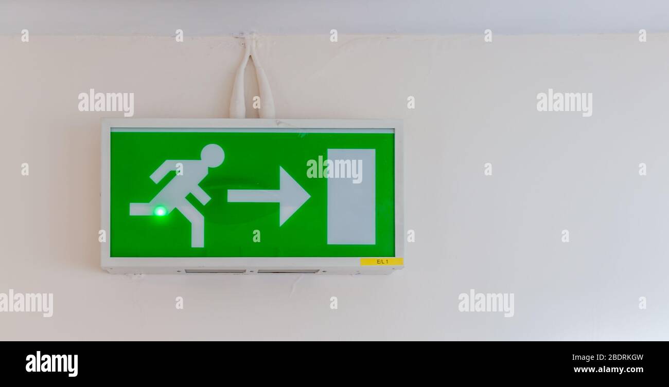 A neon green exit sign plate, man figure and arrow to the door as an ...