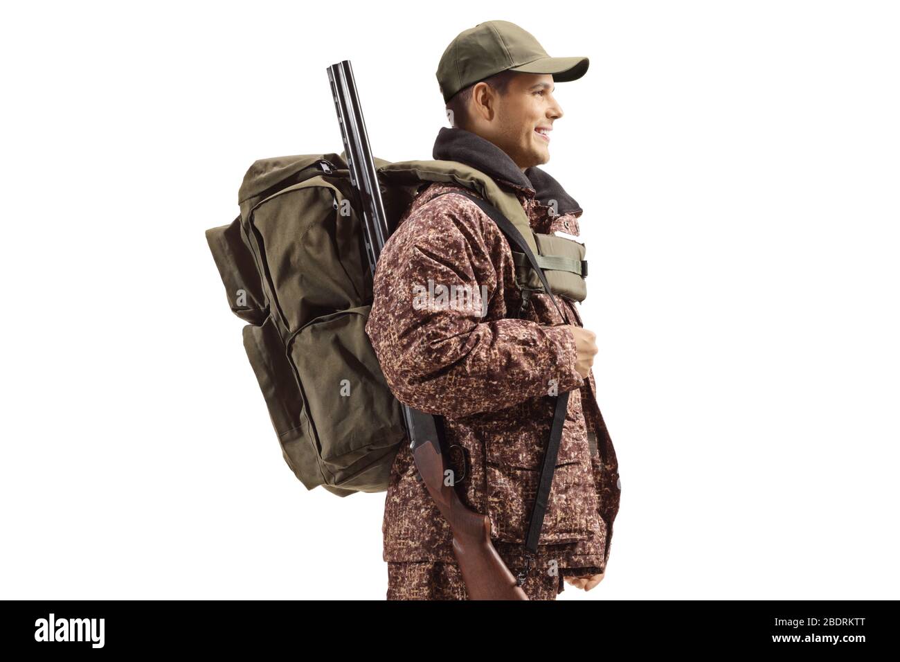 Hunter in a camouflage uniform standing with a backpack and shotgun ...