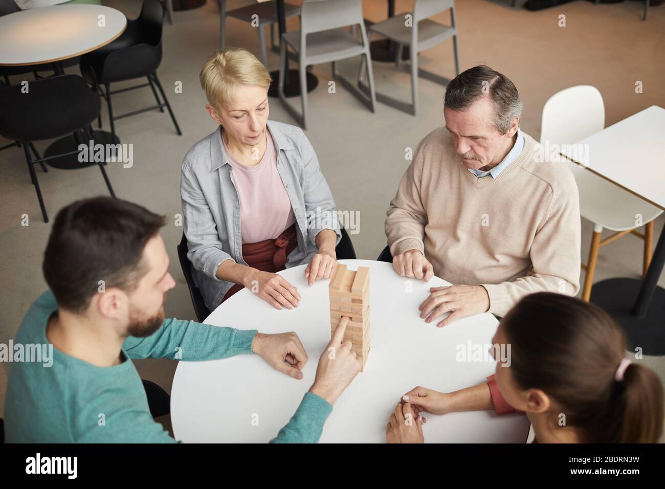 Family of four sitting around the table and playing with wooden details ...