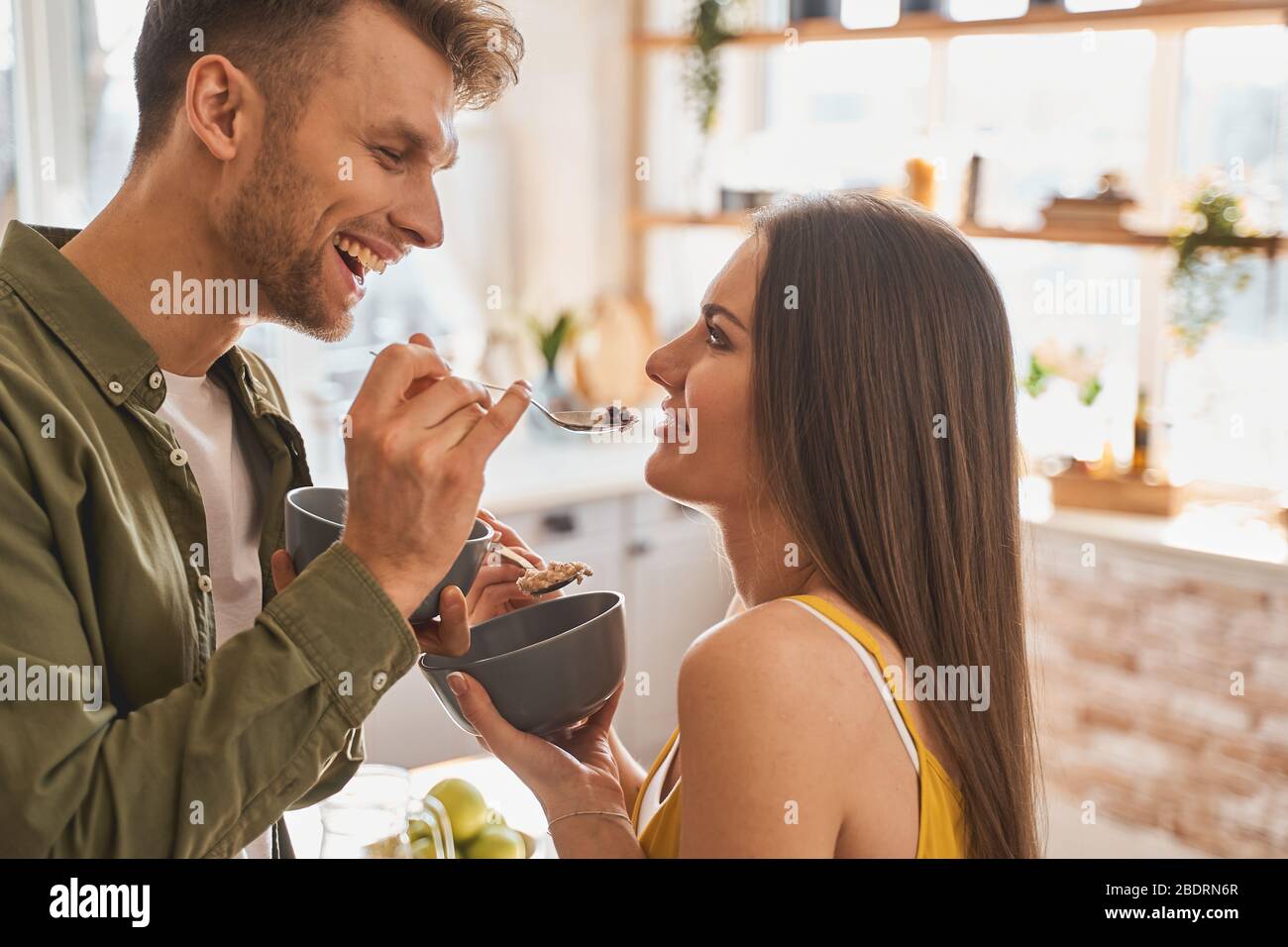 Positive delighted male person feeding his woman Stock Photo - Alamy
