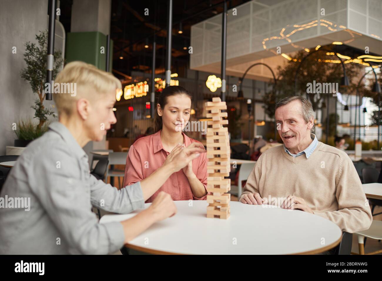 Group of friends playing in Jenga together at the table during their ...