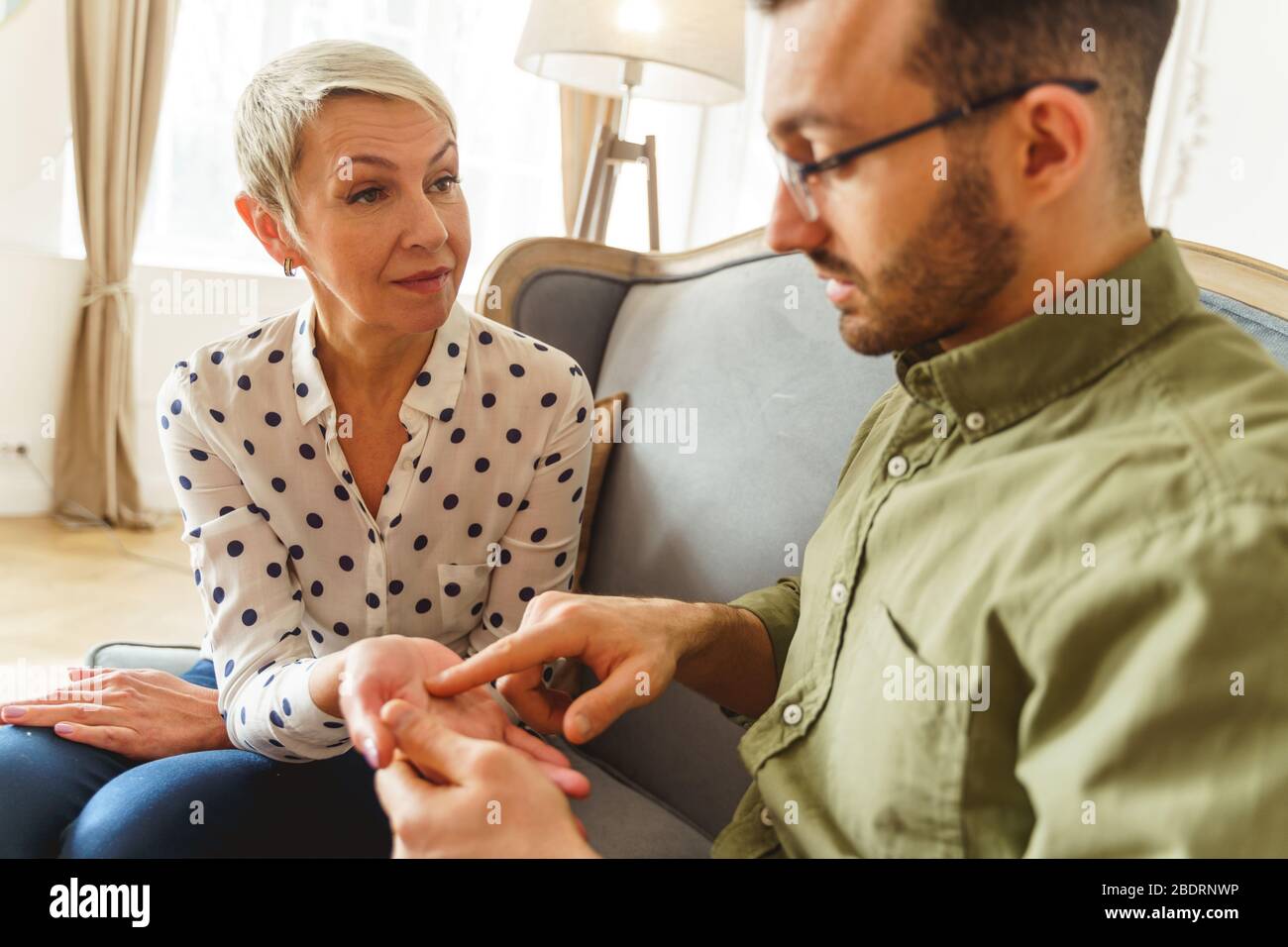 Smiling beautiful lady staring at a chiromantist Stock Photo - Alamy