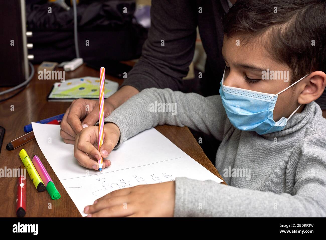 Distance education. Mother helps pre-school kid to do lessons ...