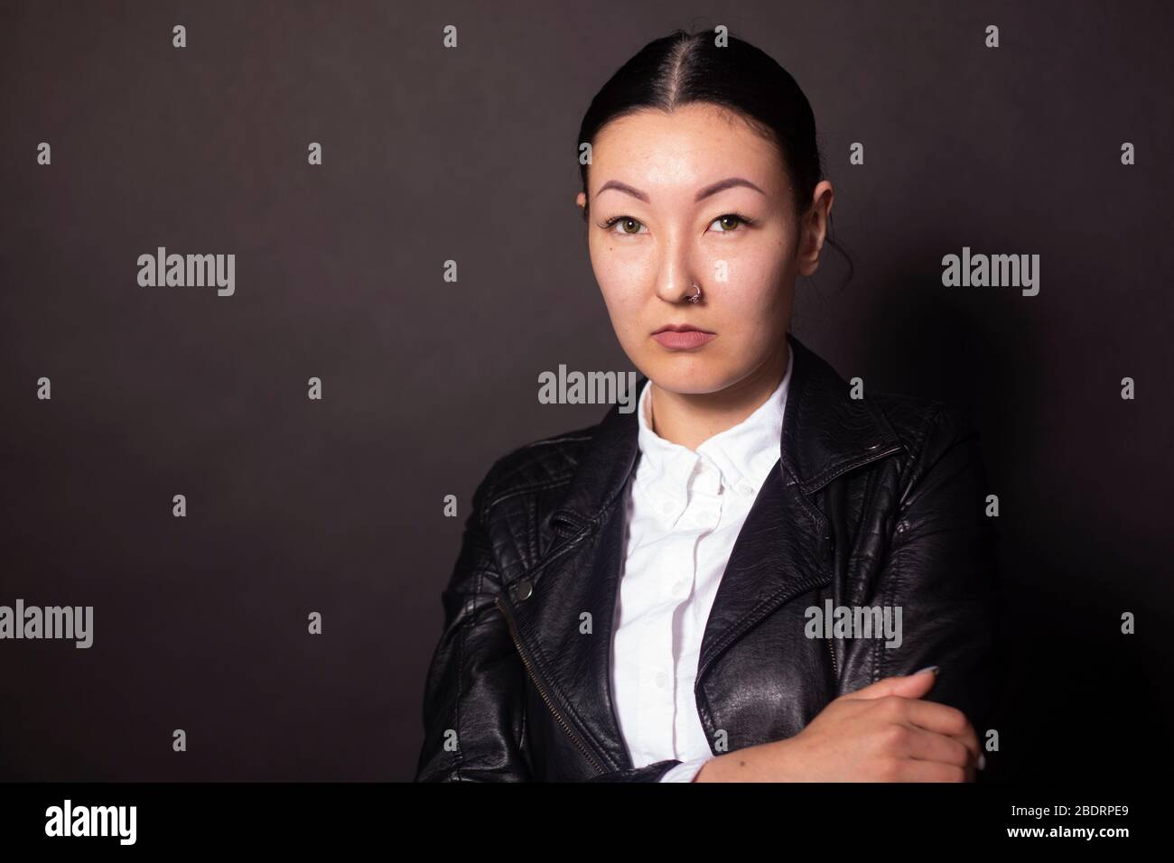 Serious asian woman looking directly at camera. Isolated on black ...