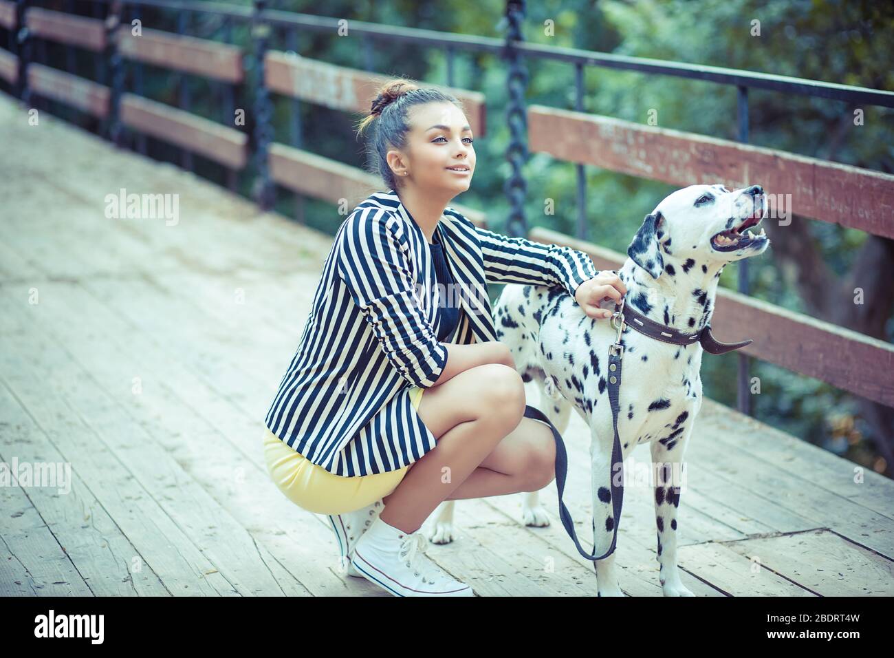 Woman pretty girl on the bridge holding her dog who is barking to ...