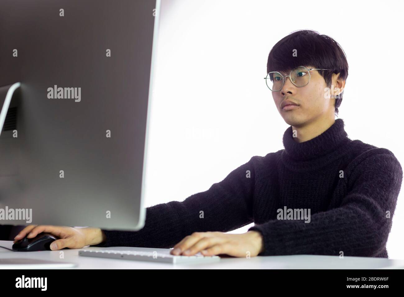 Beautiful chinese man in glasses works in office at computer. White ...