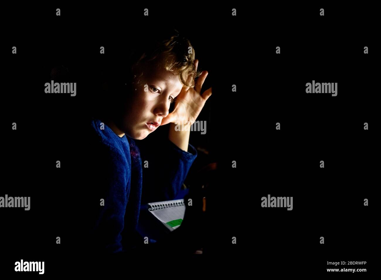 Boy studying mathematics at night alone in his dark room with ...