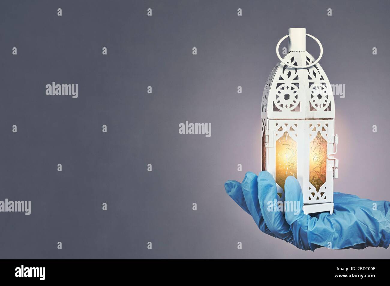 Hand in protective medical gloves holding traditional Arabic lantern ...