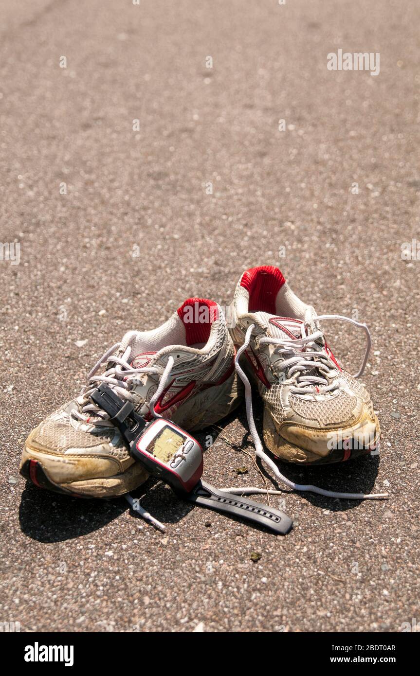 A pair of running shoes and a Garmin watch. The shoes are old and worn ...