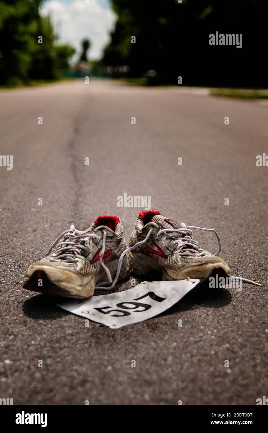An old pair of worn out running shoes with a bib #597 from a race ...