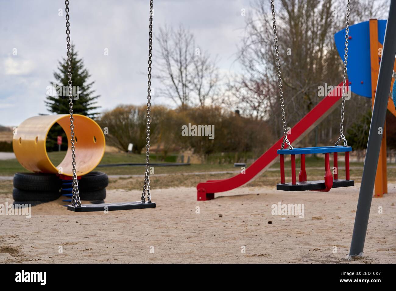 Colorful swings and rusty iron chain on cement block floor background ...