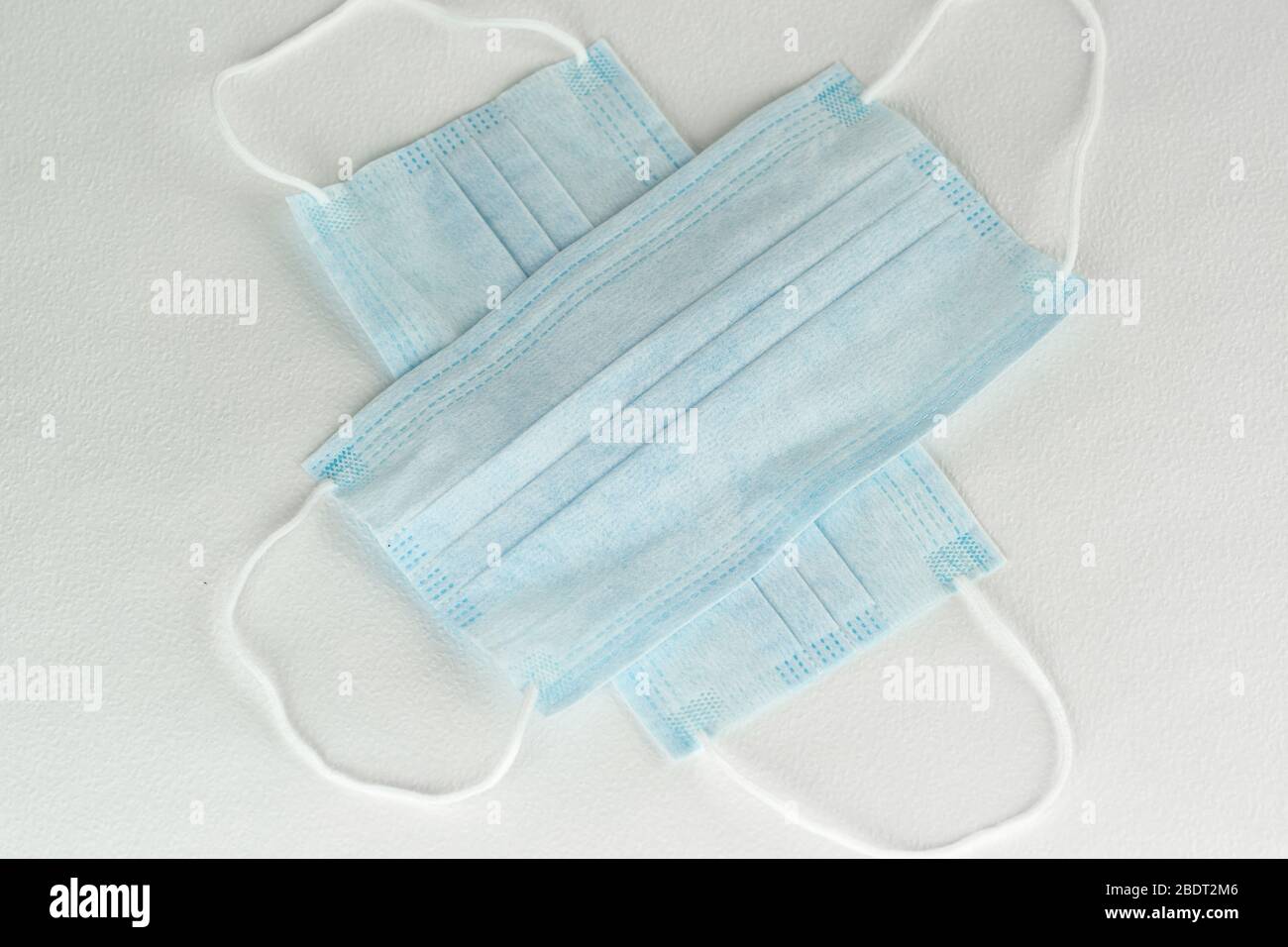 Two simple disposable medical masks made of non-woven fabric lie on a ...