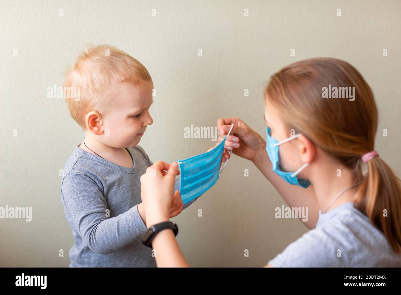 Teenage girl helping to his baby brother to wear a medical mask ...