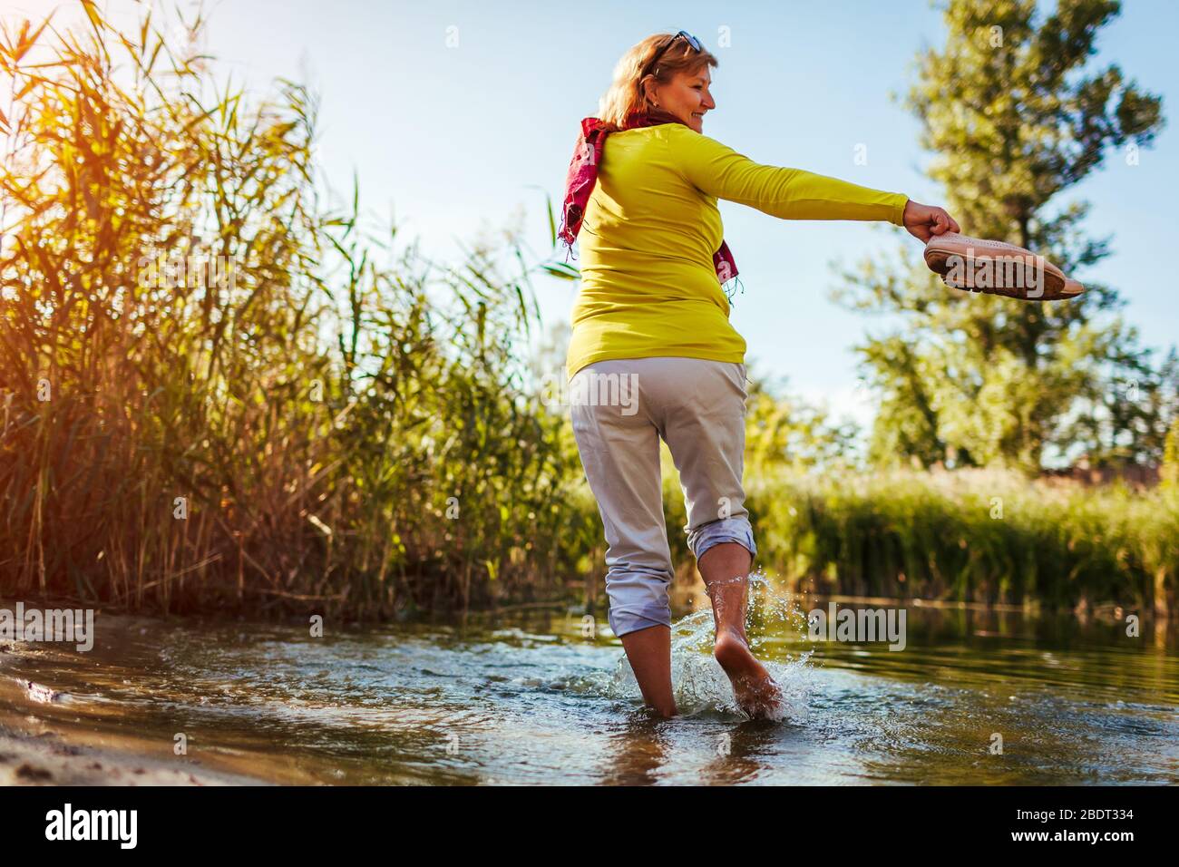 Middle-aged woman walking on river bank on spring day. Senior lady ...