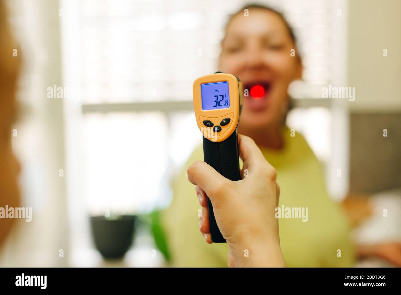 A Doctor checking a woman's temperature with a censor thermometer check ...
