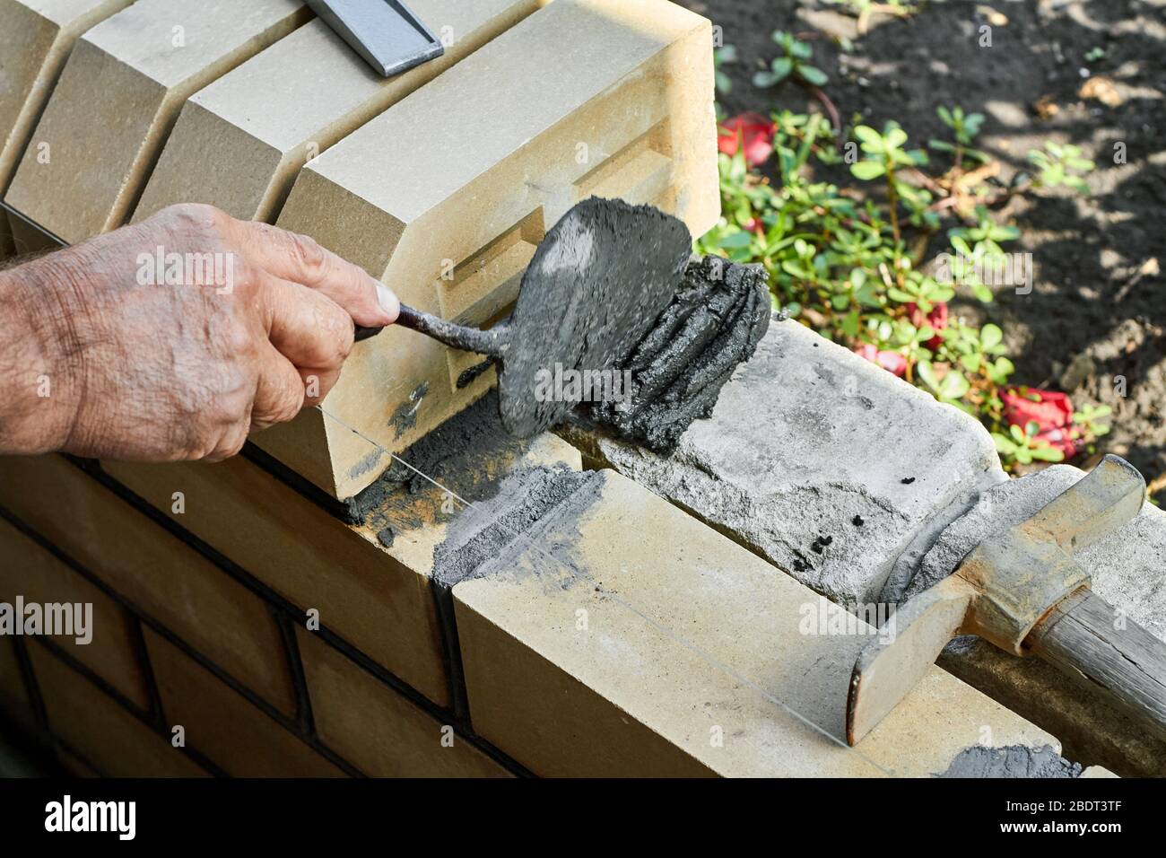 Bricklayer installing bricks on the new fence from facing bricks using ...