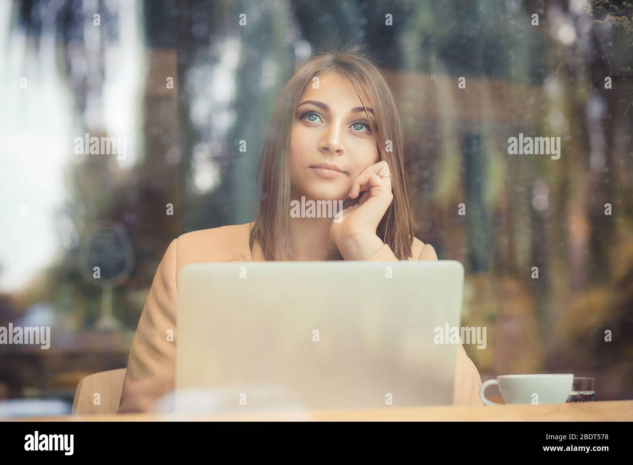 Entrepreneur with a laptop relaxing in a coffee shop and looking ...