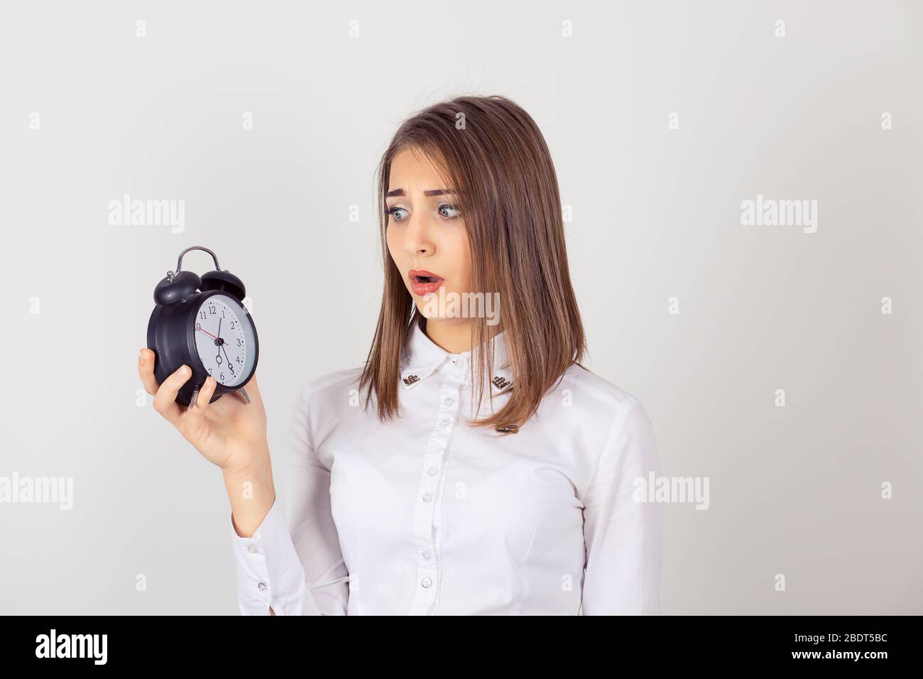 closeup headshot young business woman with alarm clock in hand isolated ...