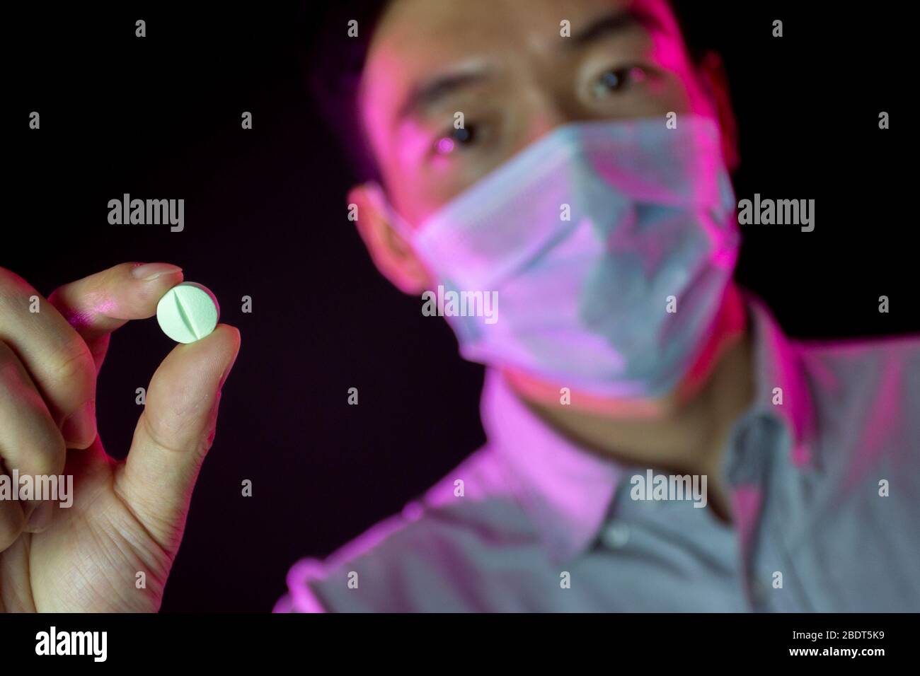 Pill in hand of asian man in medical mask against covid-19. Black ...
