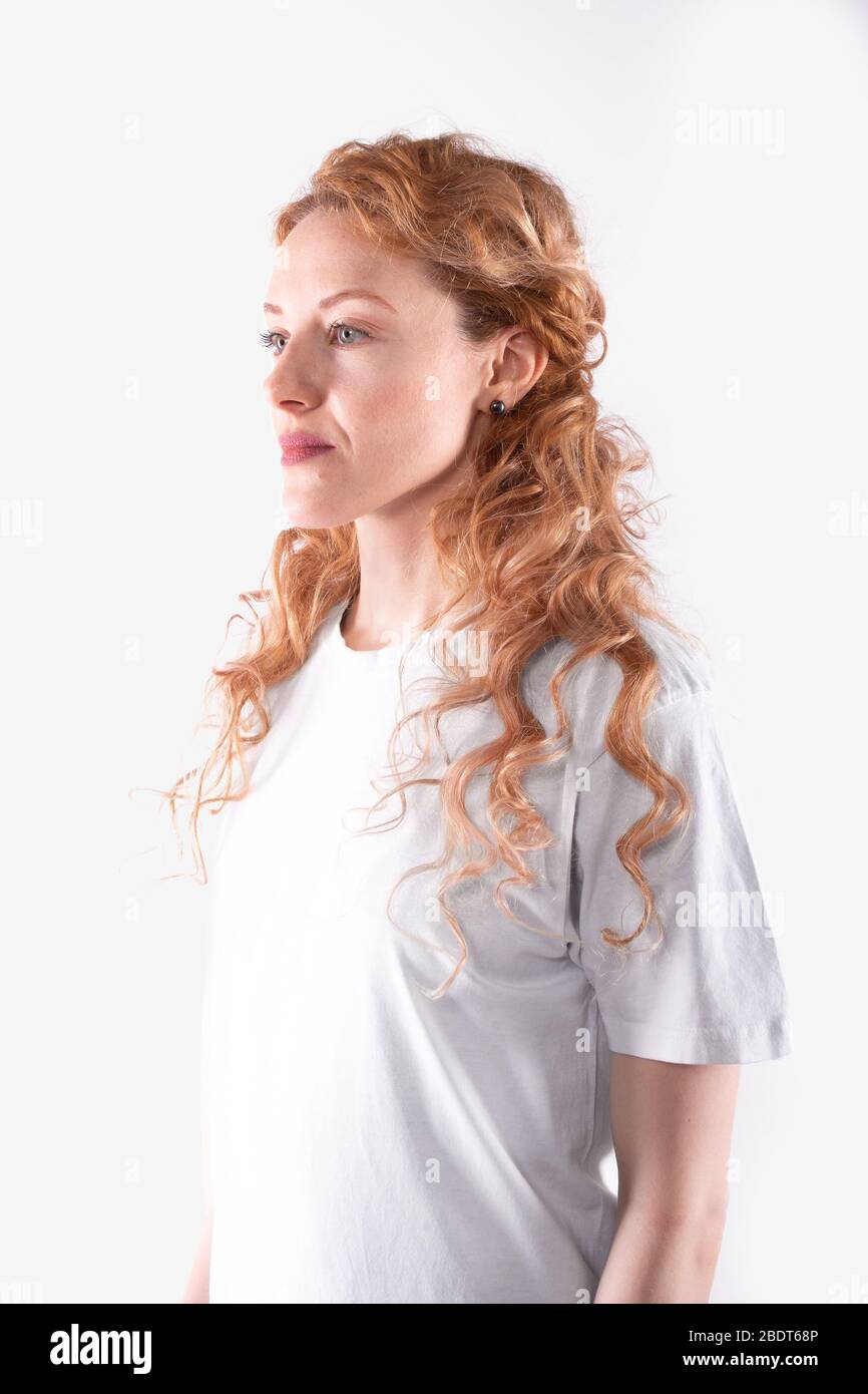 Beautiful girl with fair curly hair stands half-sides and looks ...