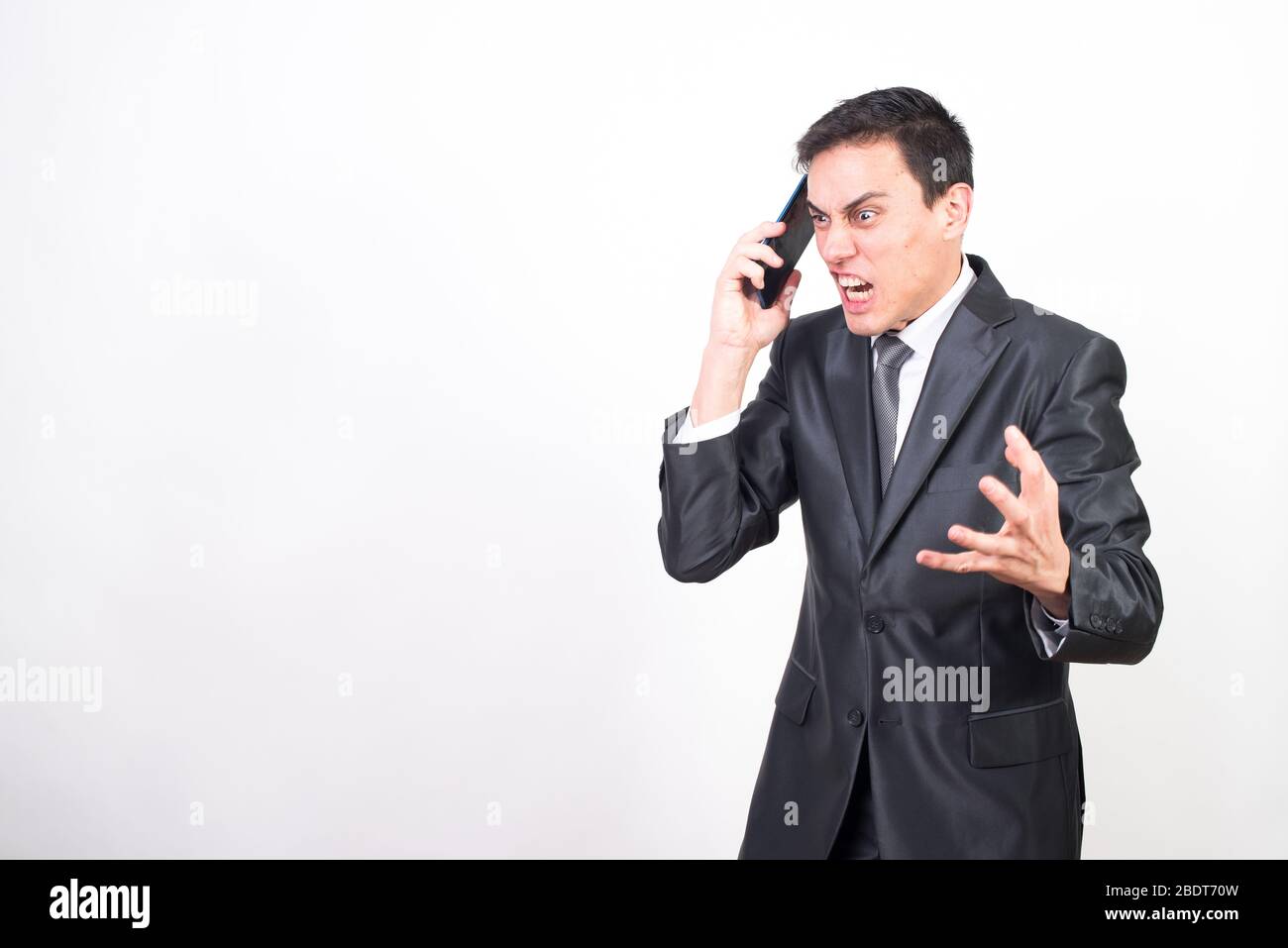Man in suit talking angry on mobile. White background, medium shot ...