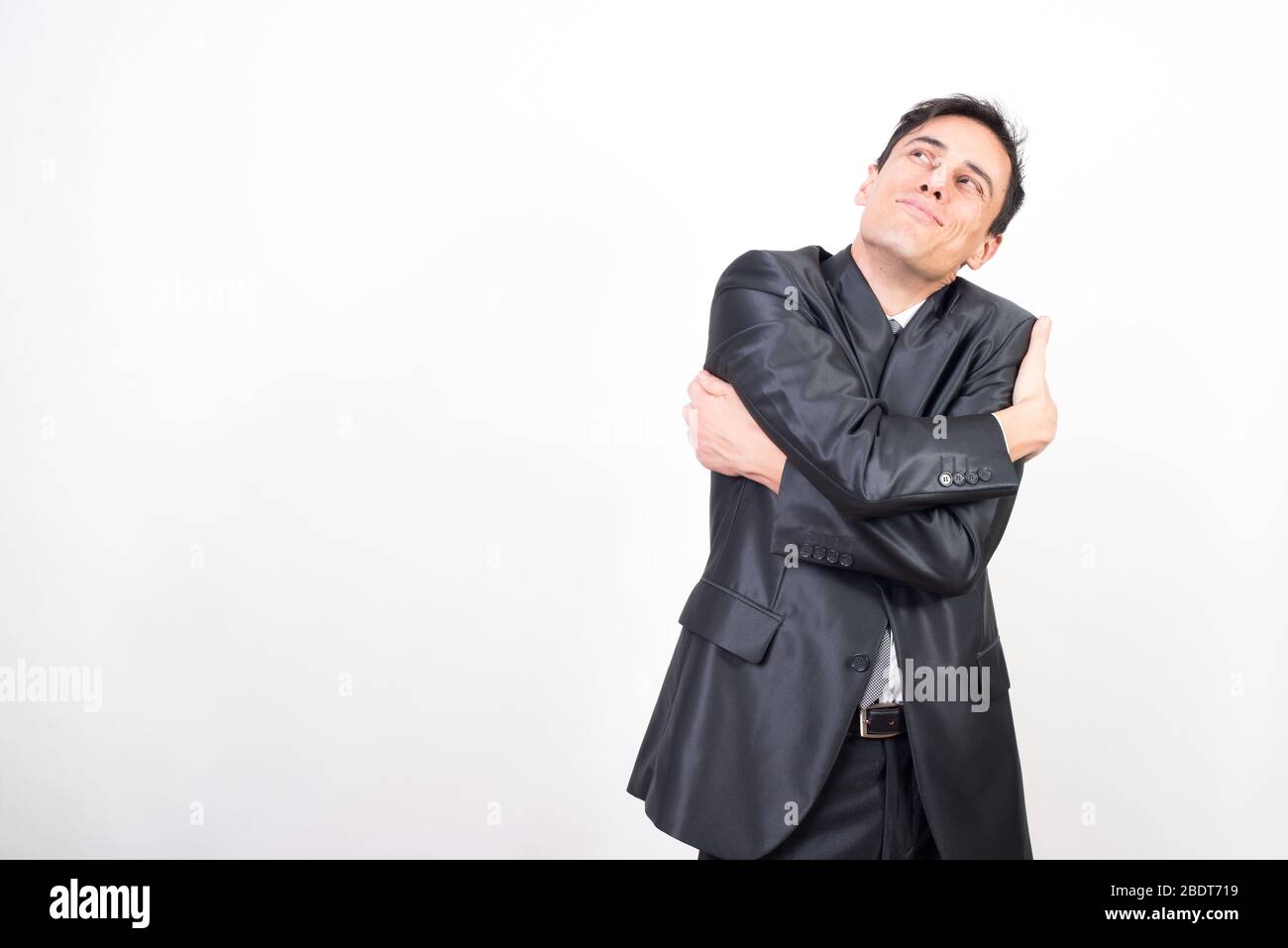 Man in suite in love hugging himself. white background, medium shot ...