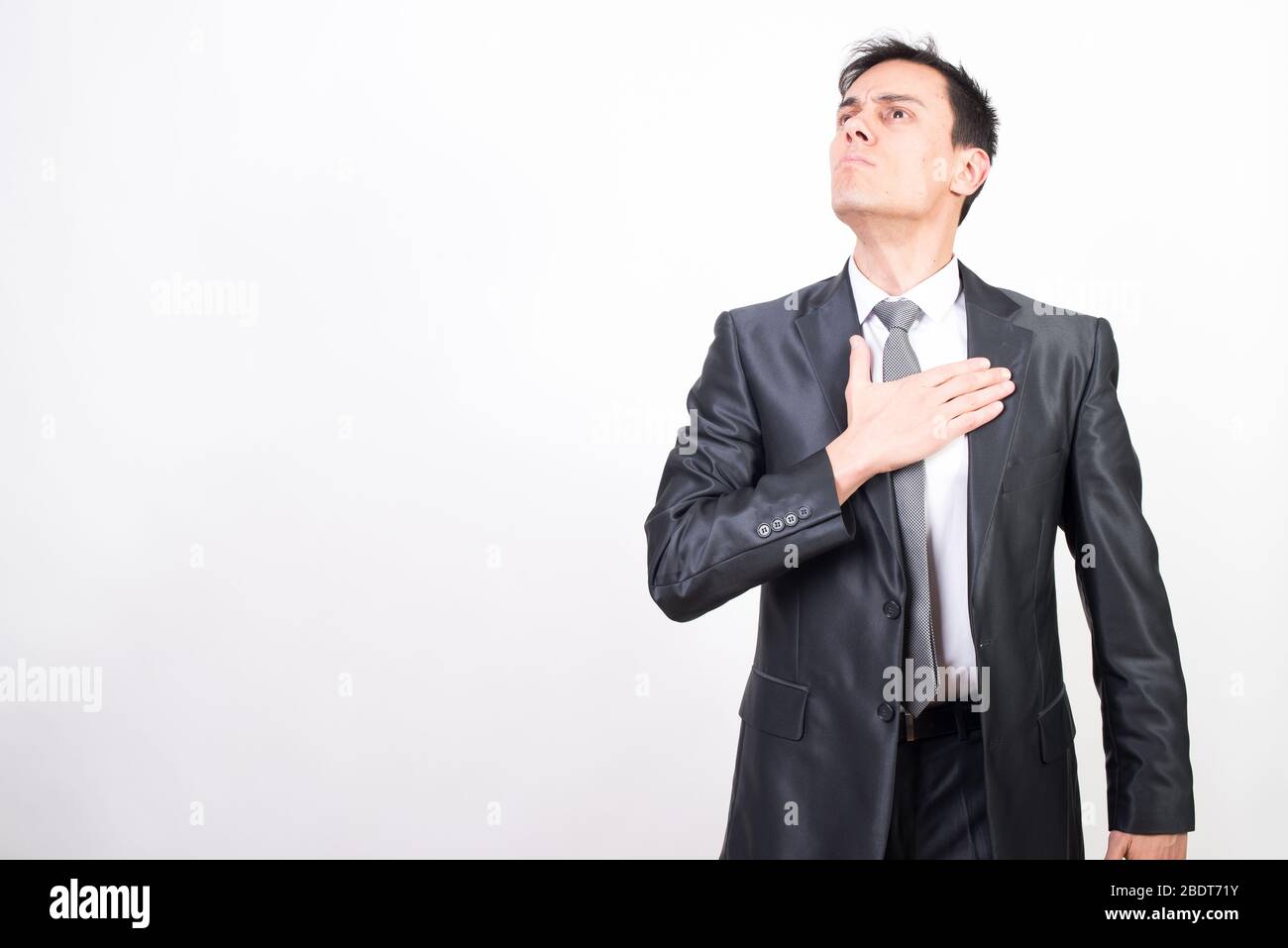 Honest man in suit with hand in heart, white background, medium shot ...