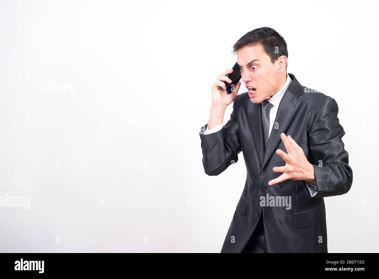 Man in suit talking angry on mobile. White background, medium shot ...