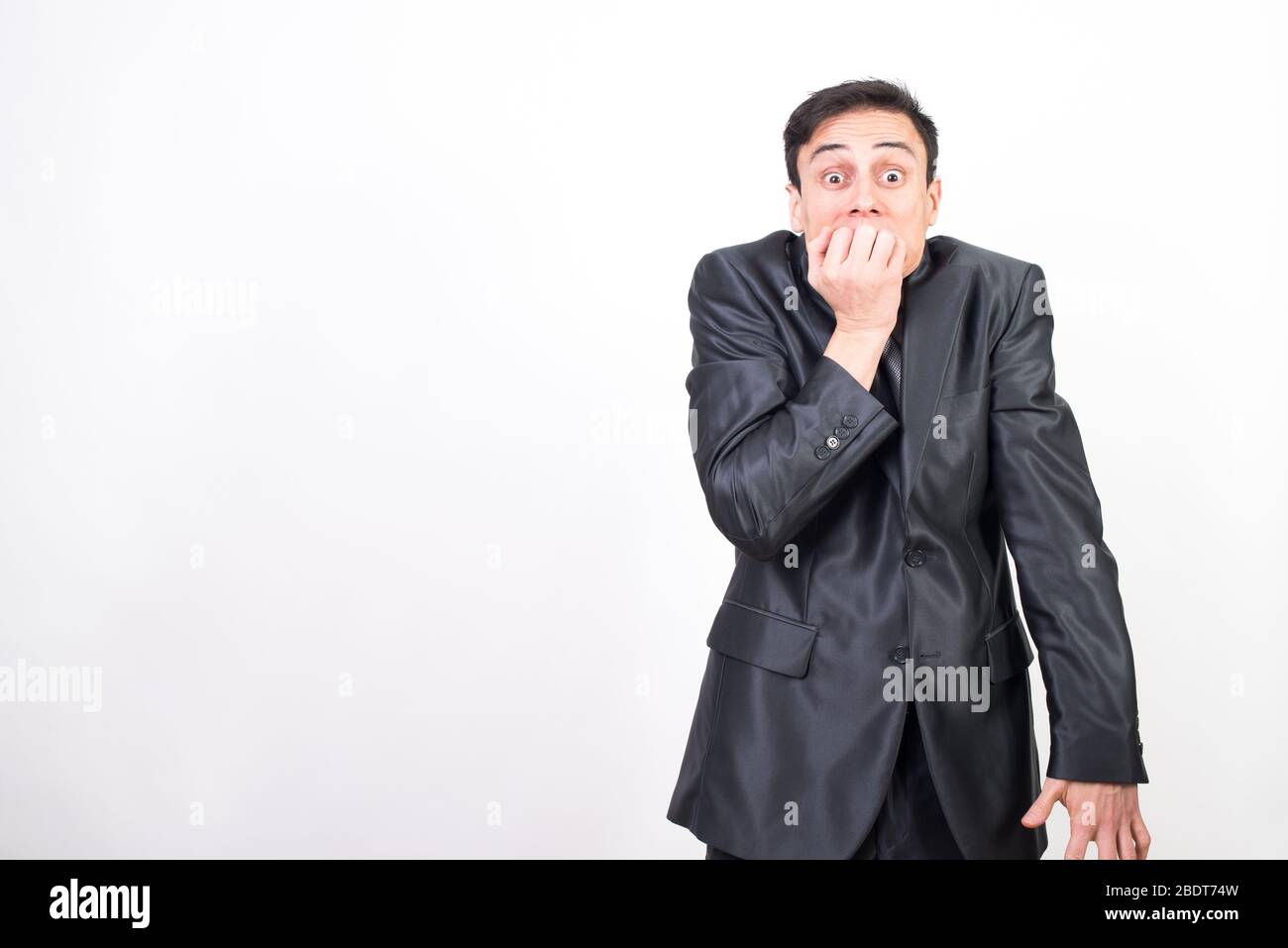 Nervous man in suit eating his nails. white background, medium shot ...