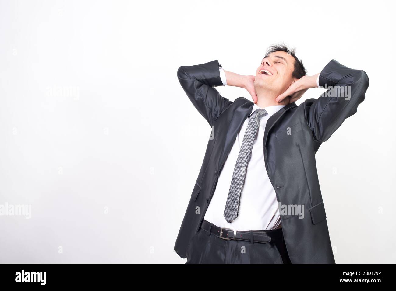 Relaxed man in suit leaning back with his hands on the back of his neck ...