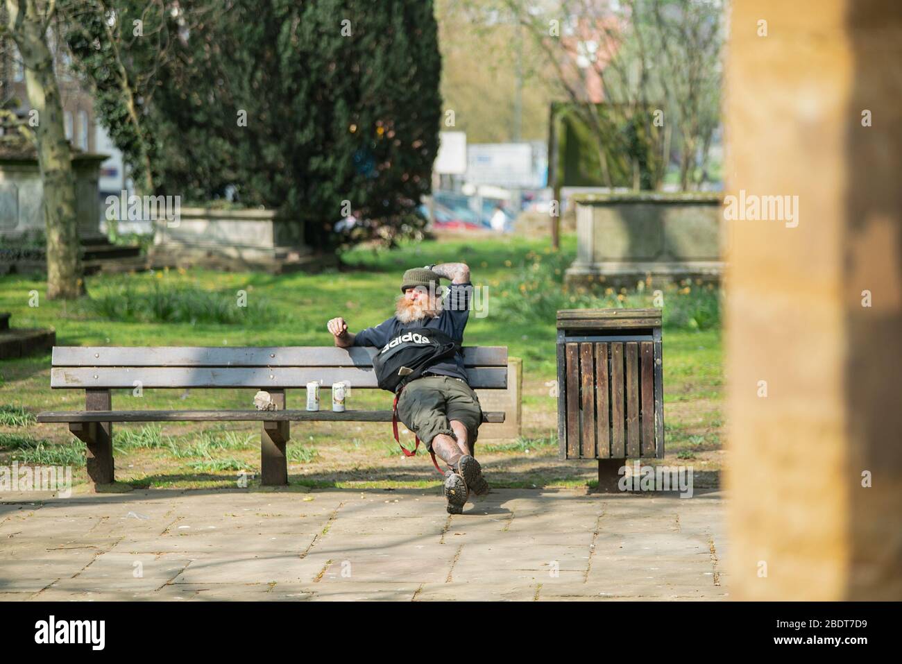 A man sitting on a bench in a small park and drinking cider, enjoys the ...