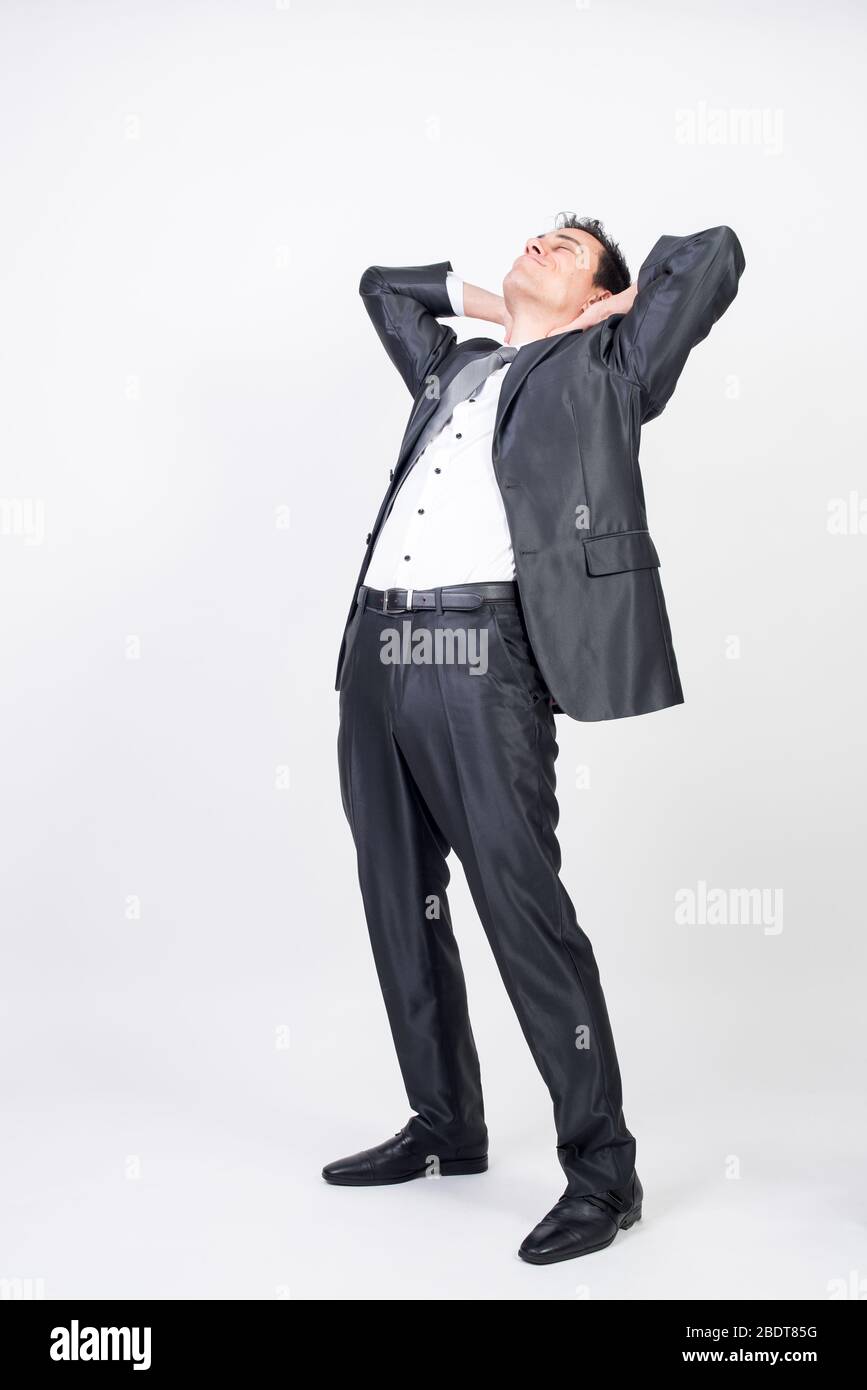 Relaxed man in suit leaning back with his hands on the back of his neck ...