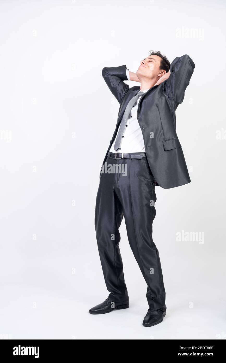 Relaxed man in suit leaning back with his hands on the back of his neck ...