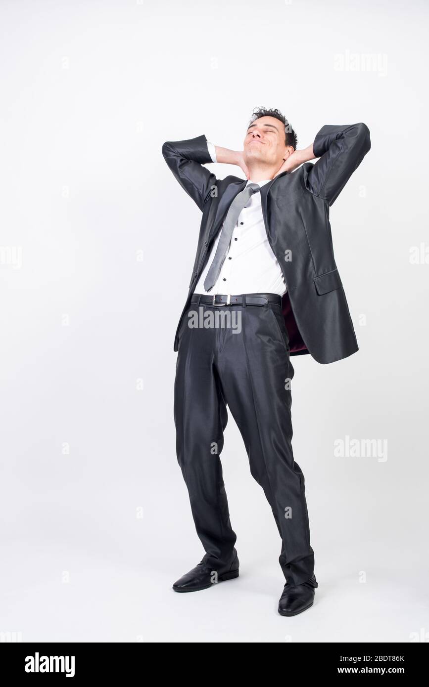 Relaxed man in suit leaning back with his hands on the back of his neck ...