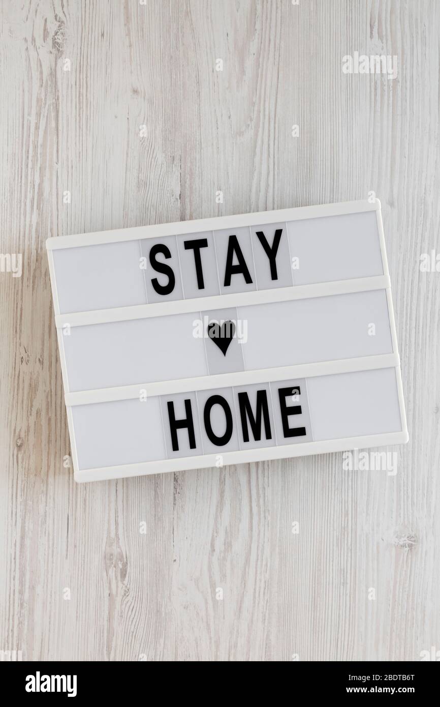 'Stay home' words on a lightbox on a white wooden surface, top view ...