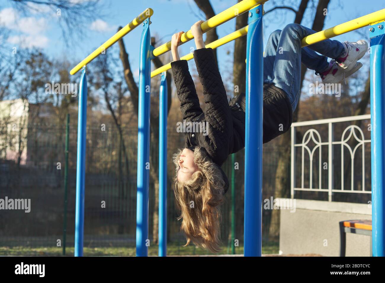 Girl child hanging upside down on outdoor sports playground with eyes ...