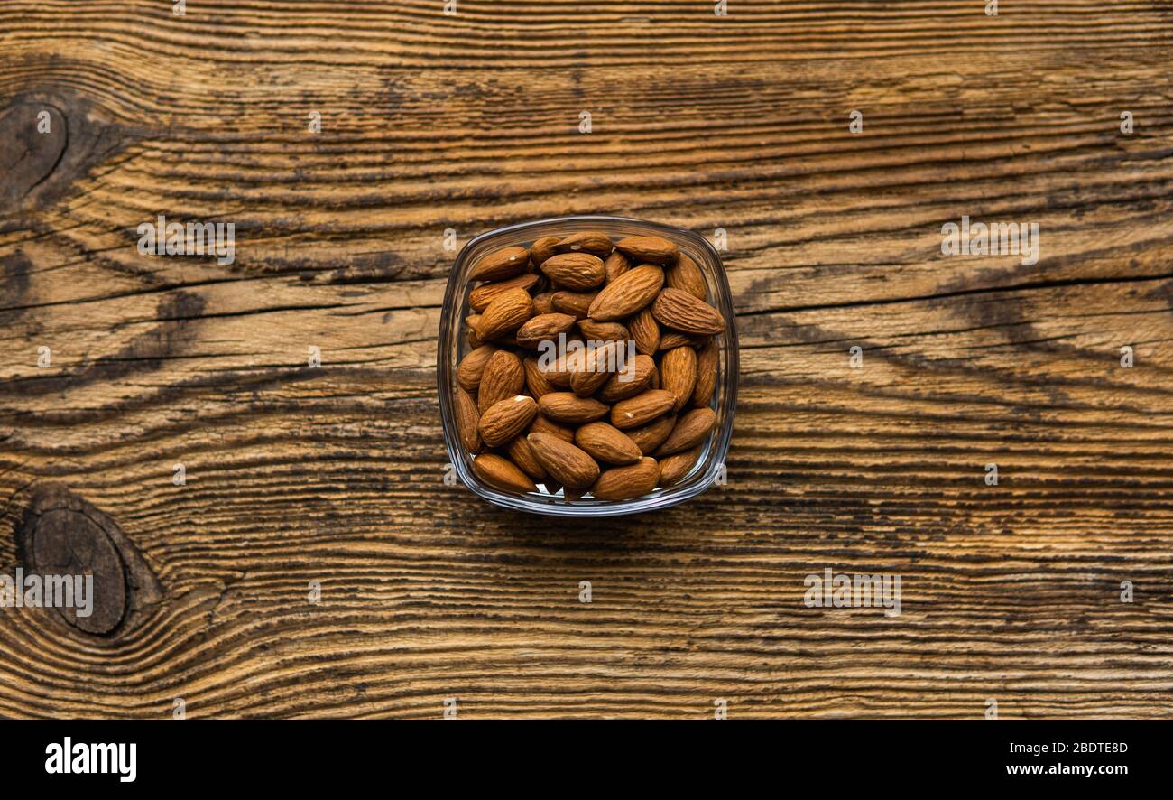 Almonds in a small plate on a vintage wooden table as a background with ...