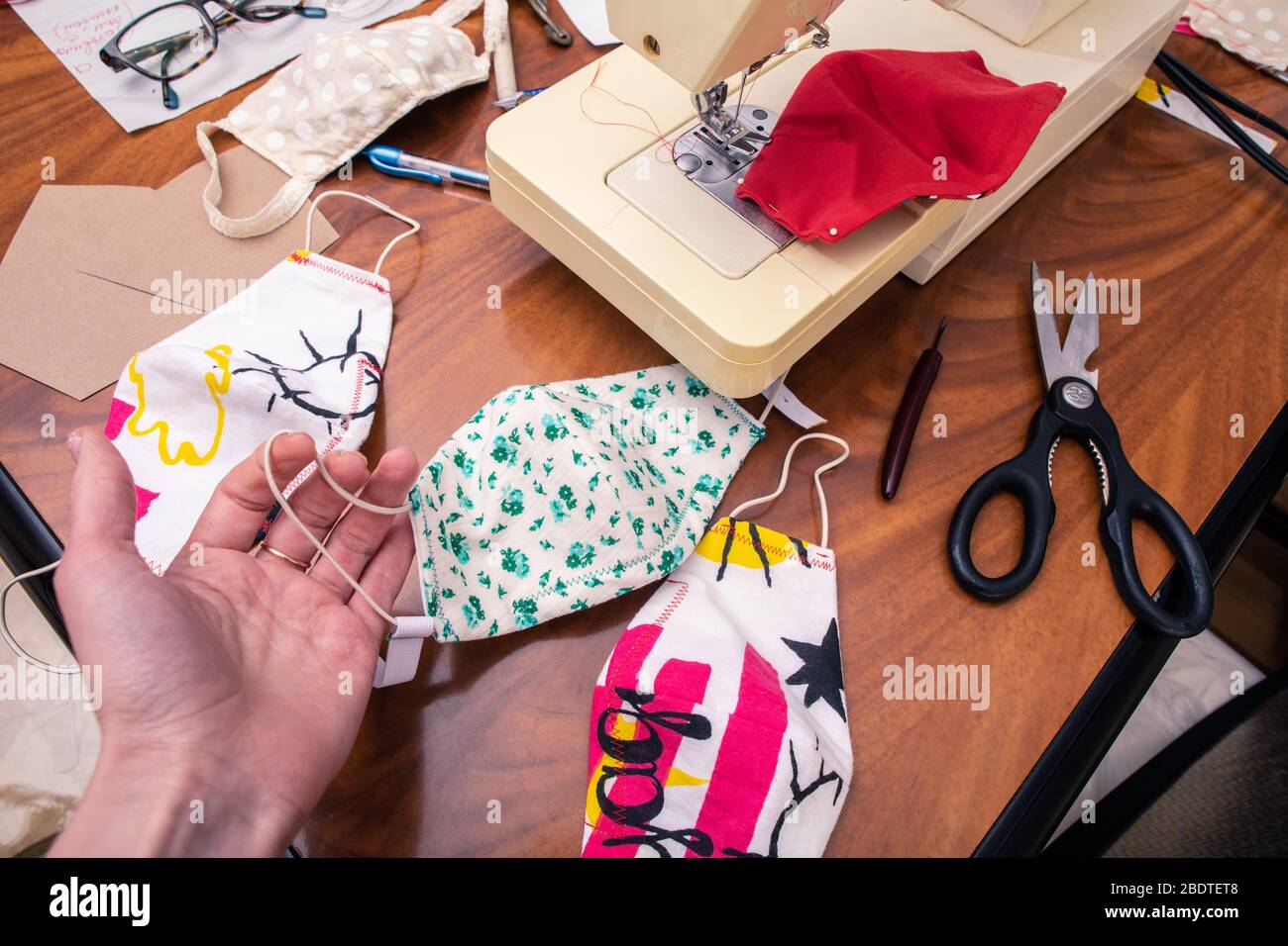 A stack of fabric cloth sewn masks with colorful patterns. People are ...