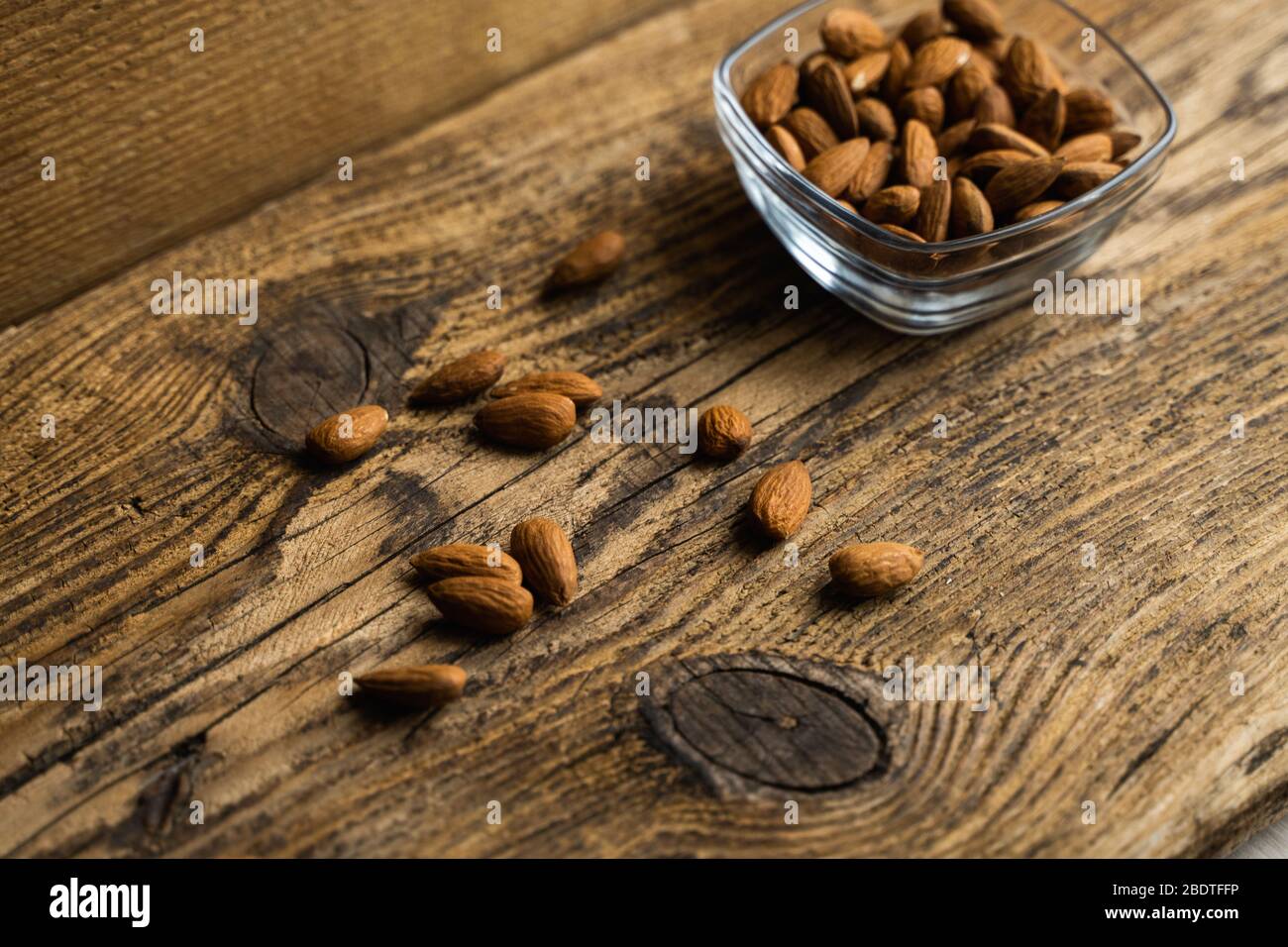 Almonds in a small plate with scattered nuts of almonds around a plate ...